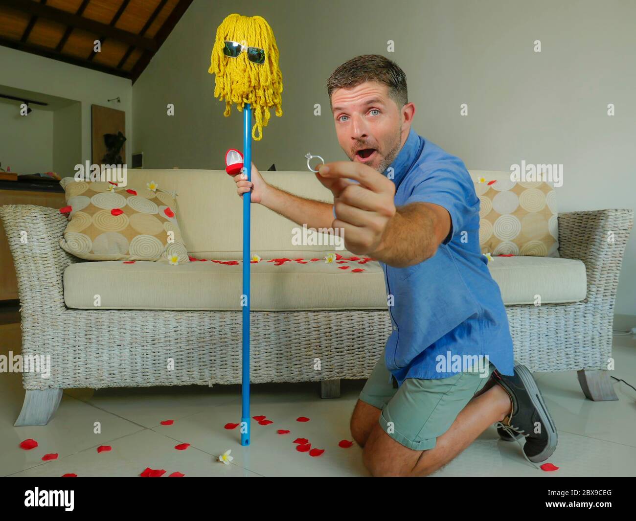 funny portrait of young weird crazy and happy man holding mop with ...