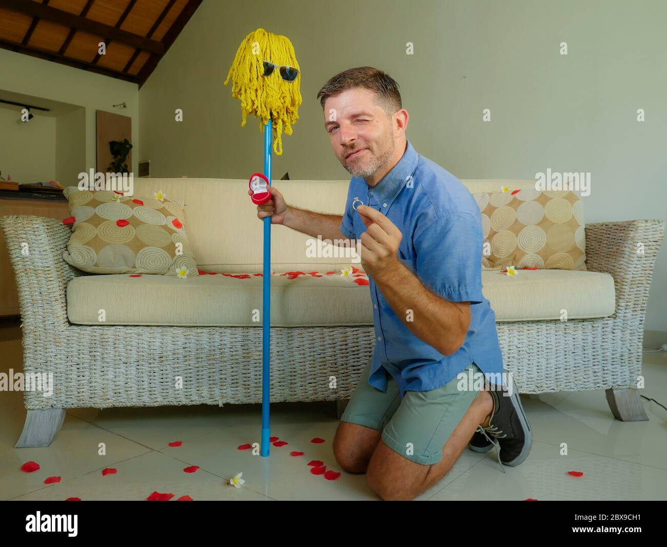funny portrait of young weird crazy and happy man holding mop with ...
