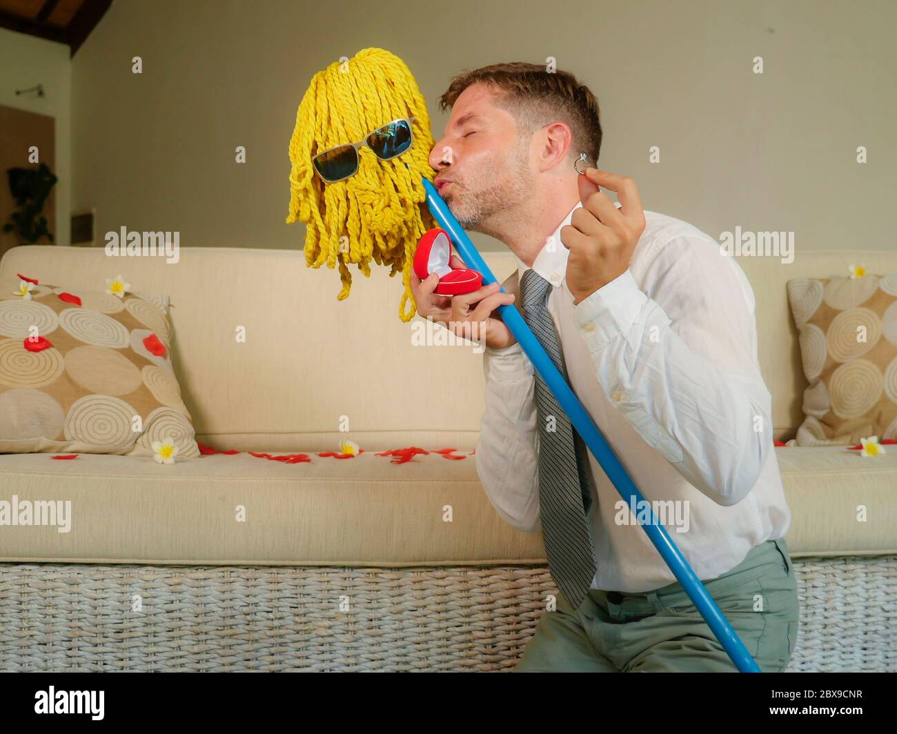 funny portrait of young weird crazy and happy man holding mop with ...