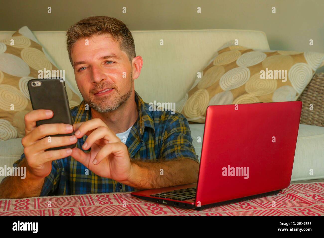 lifestyle home portrait of young happy and attractive man at home sofa couch working on laptop ...