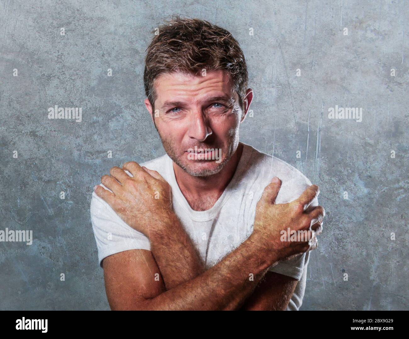 portrait of sad and depressed man hugging and embracing himself ...