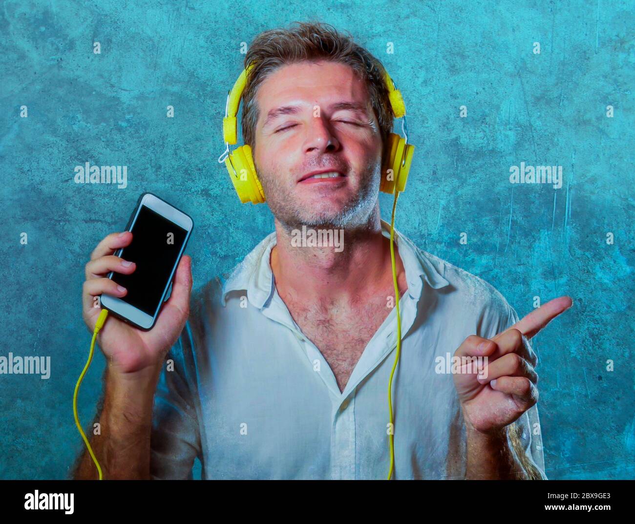 young attractive and happy cool man listening to music song with yellow ...