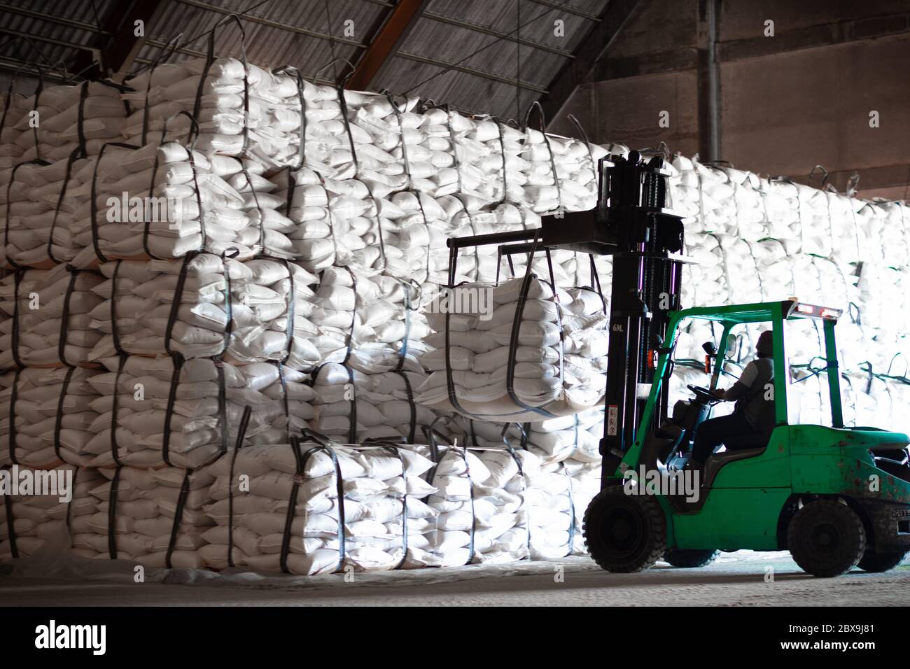 Forklift carries jumbo bag of refine white sugar to put on the stack ...