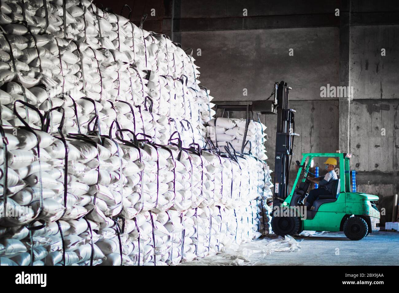 Forklift carries jumbo bag of refine white sugar to put on the stack ...