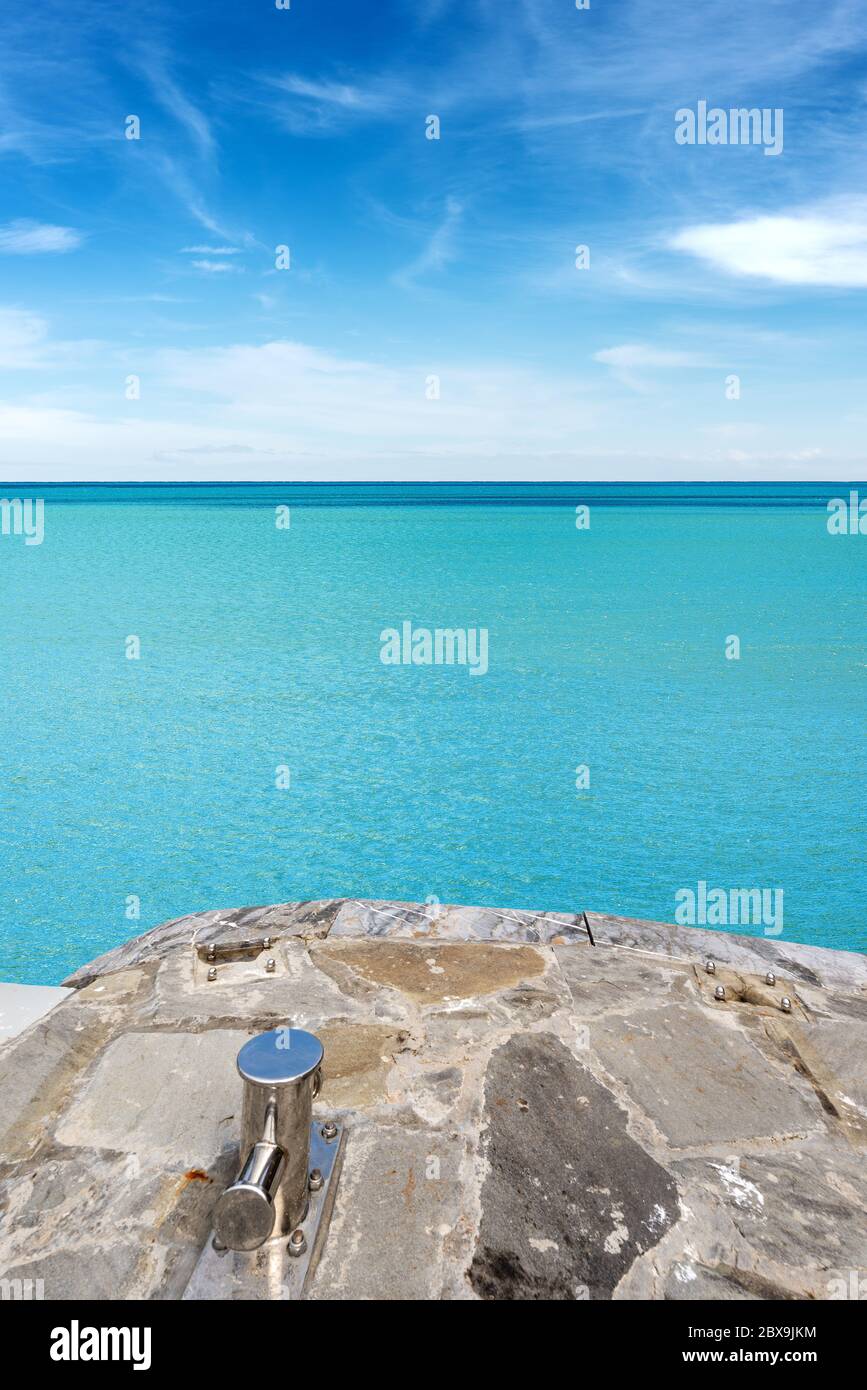 Stone jetty with an empty mooring bollard and turquoise seascape with ...