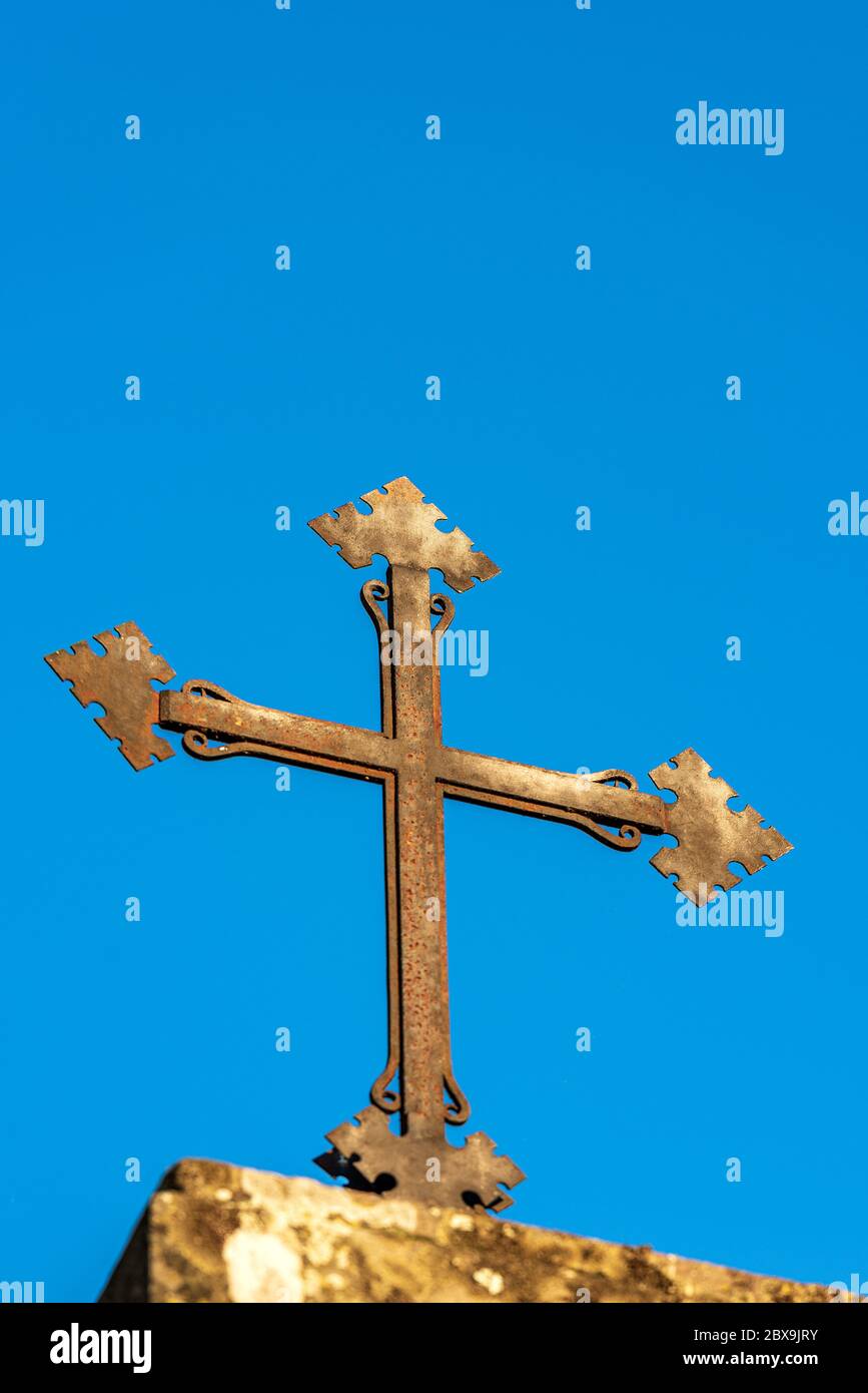 Closeup of an ancient Christian cross in wrought iron on a clear blue ...