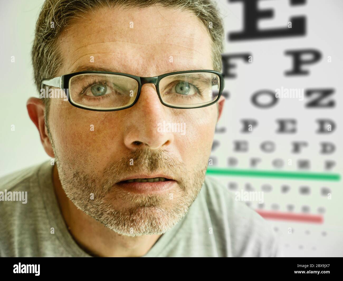Attractive man checking vision trying glasses at optometrist . Cheerful ...