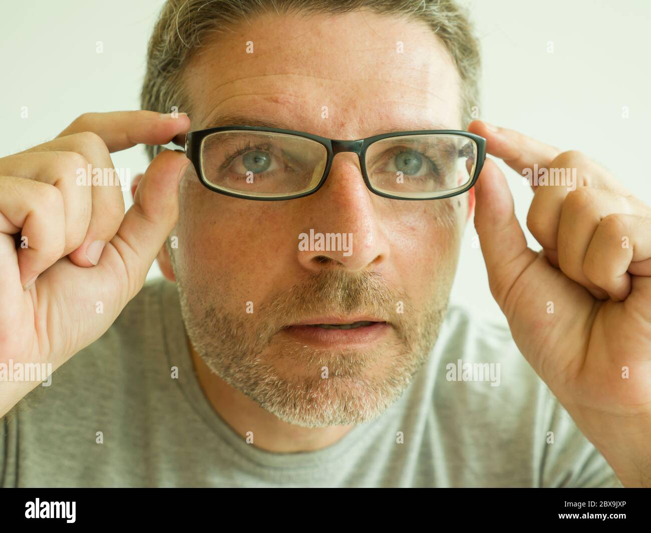 close up face portrait of attractive man checking vision trying glasses ...
