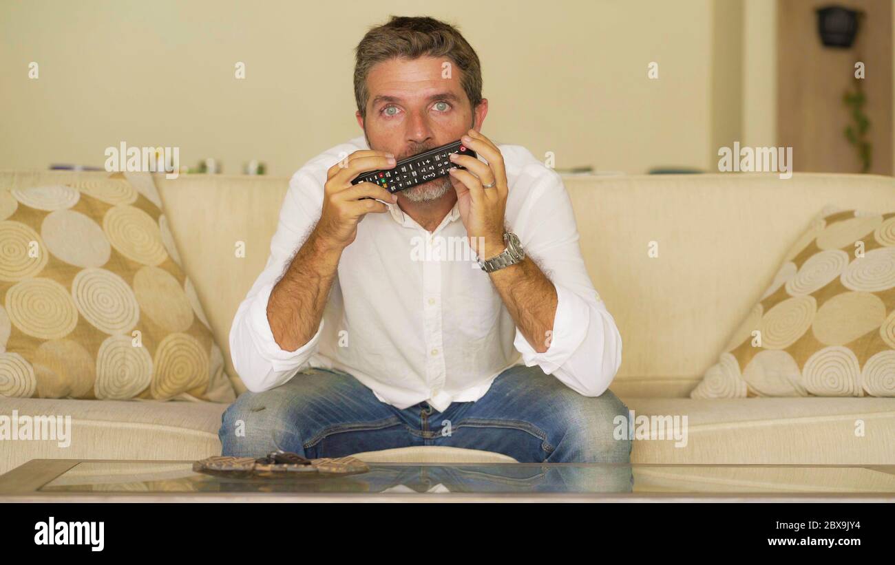 attractive excited and nervous man watching television in intense ...