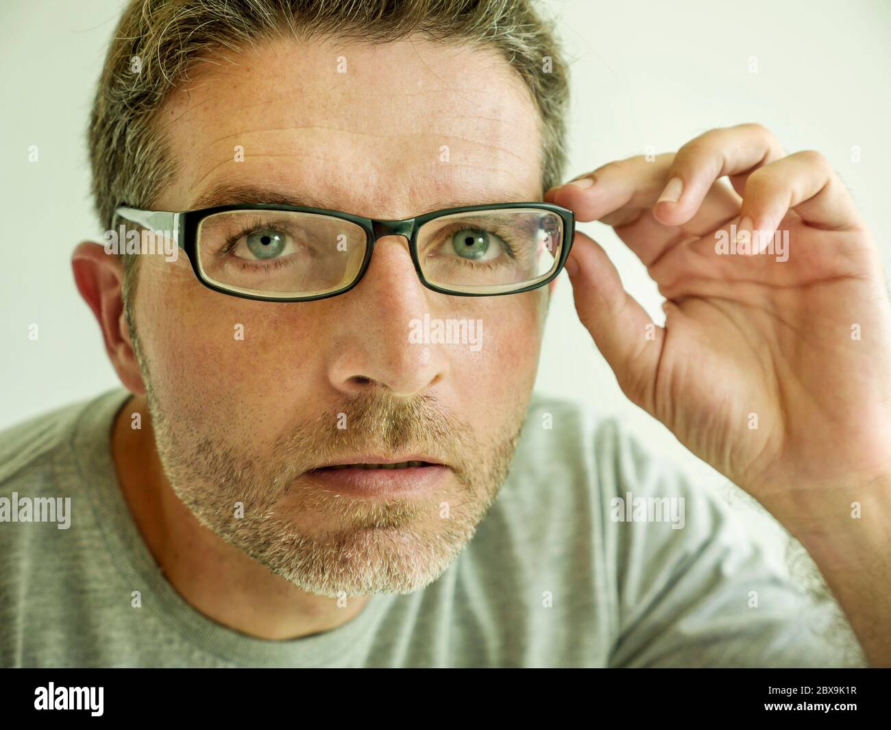 close up face portrait of attractive man checking vision trying glasses ...