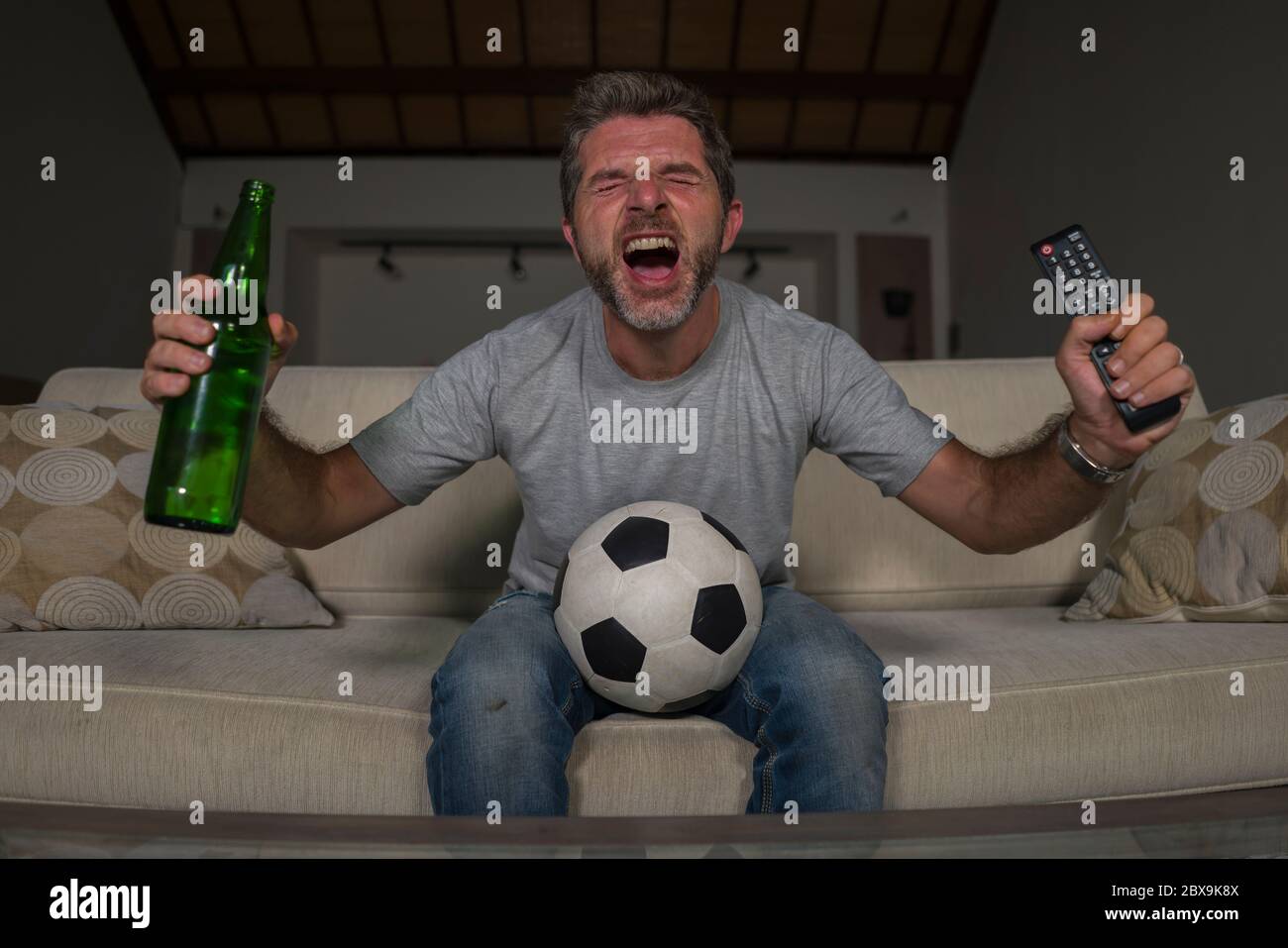crazy excited man watching football game holding soccer ball ...