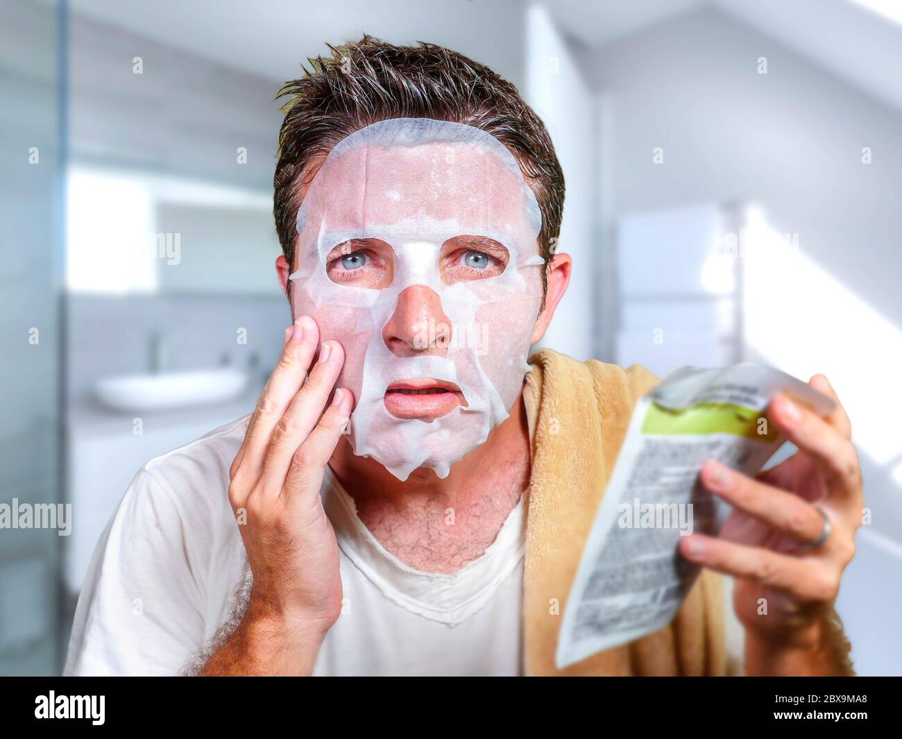 lifestyle bathroom portrait of young weird and funny man at home trying ...