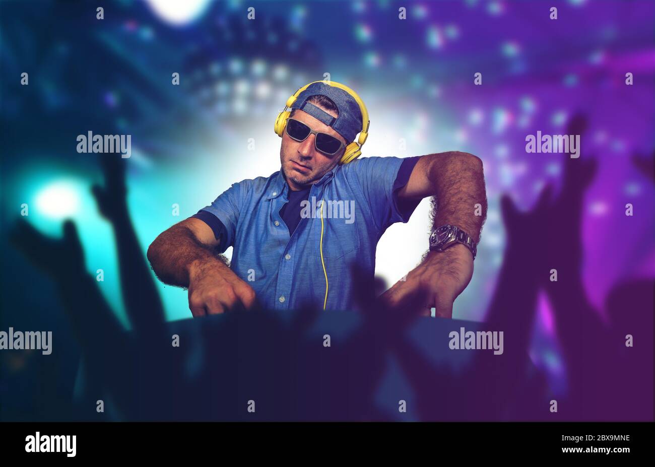 young happy and cool deejay playing music at party event in night club ...