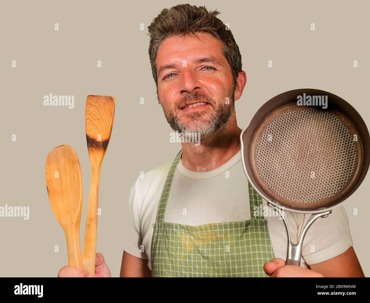 young happy and attractive home cook man in apron smiling cheerful and ...