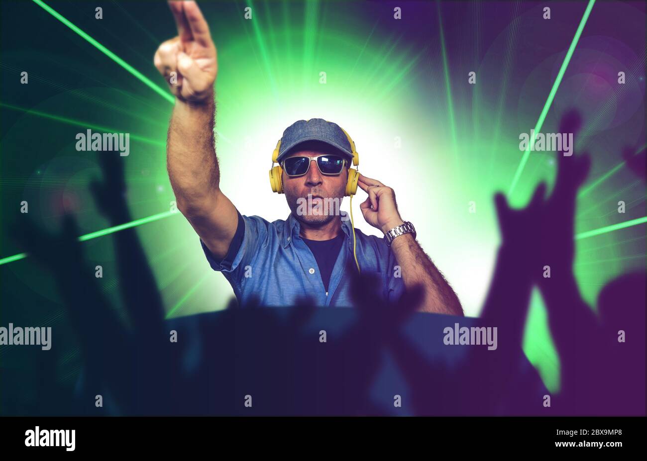 young happy and cool deejay playing music at party event in night club ...