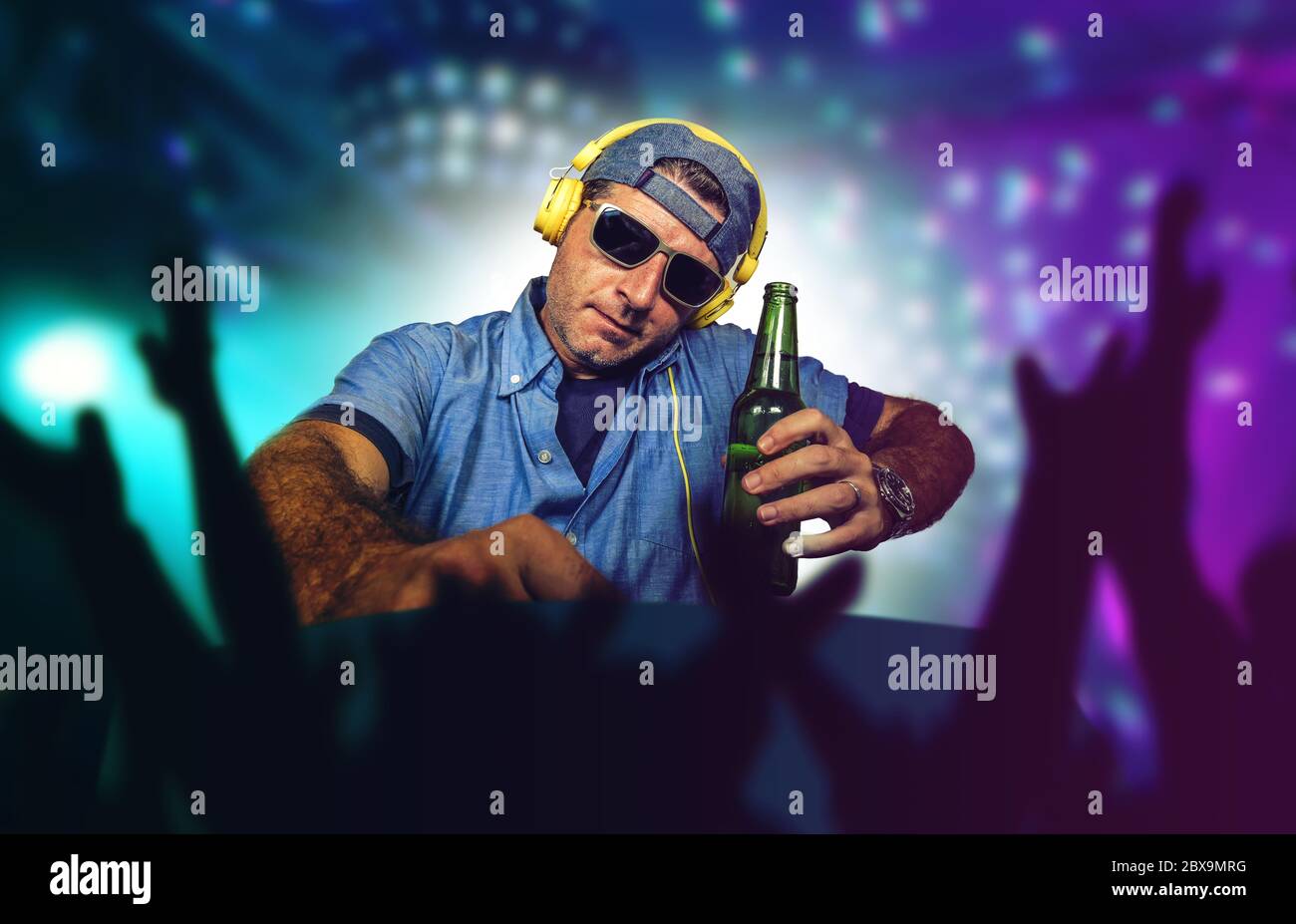 young happy and cool deejay playing music at party event in night club ...