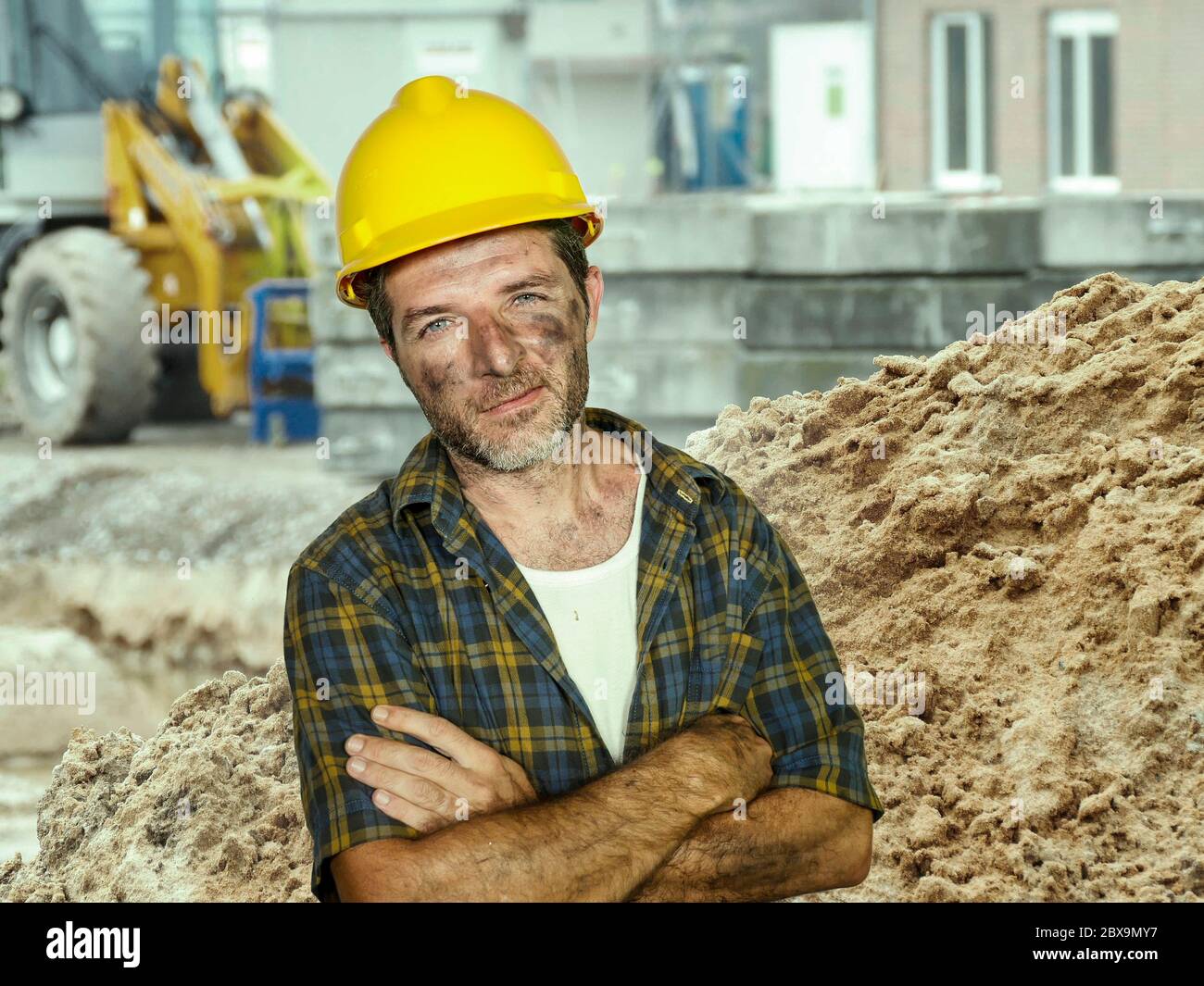 lifestyle portrait of young attractive and confident contractor or construction worker man with ...