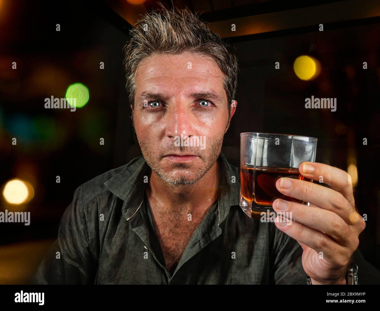 young messy and wasted man drunk at night club or bar drinking whiskey ...