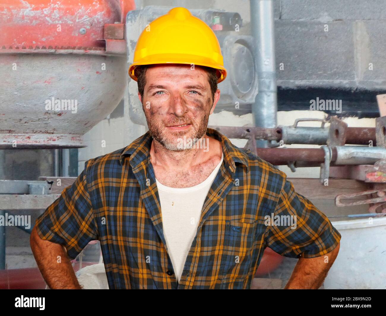 lifestyle portrait of young attractive and confident contractor or construction worker man with ...
