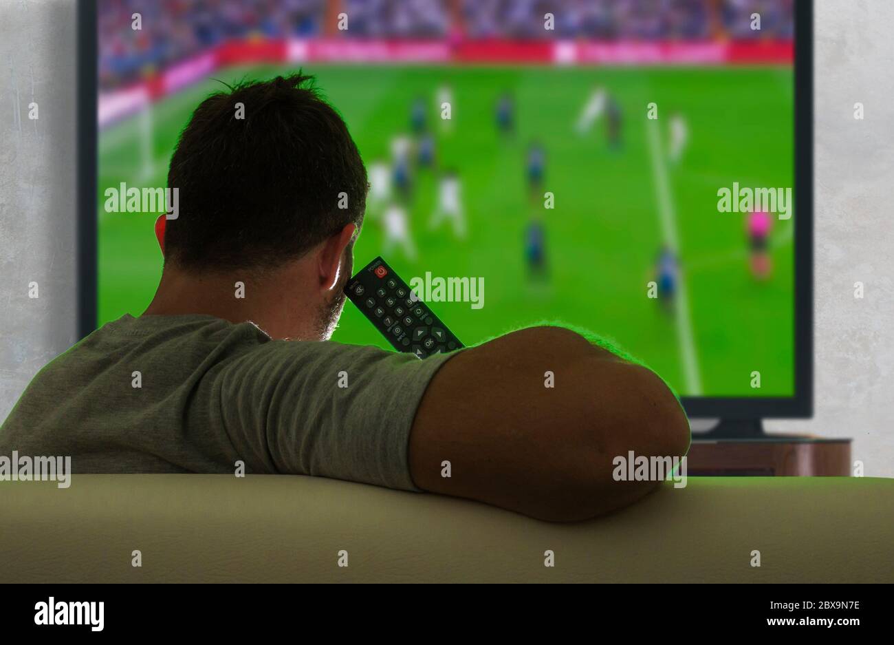 view from behind of young soccer fan man watching European football ...