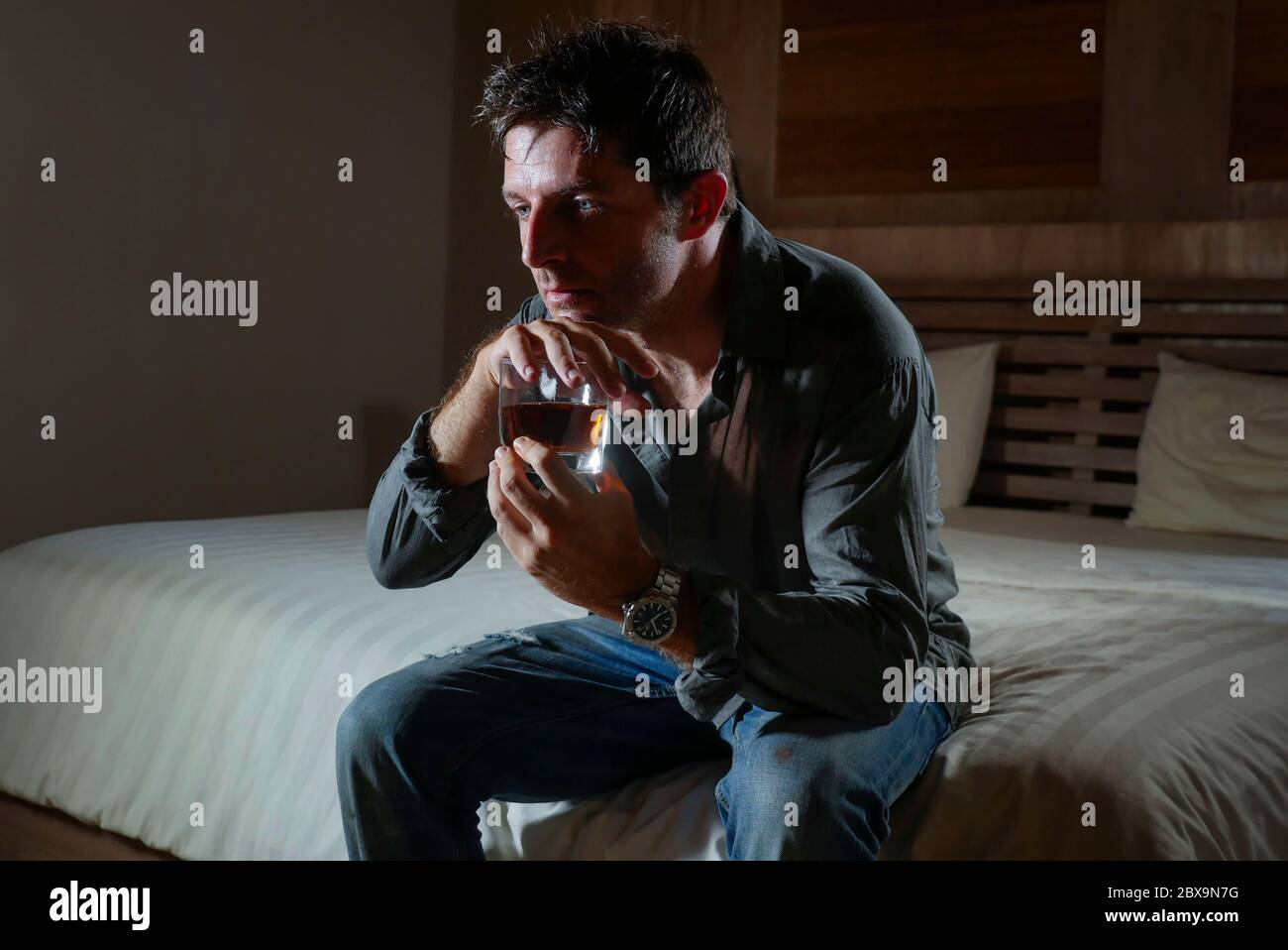 young messy and wasted drunk man drinking whiskey glass at home sitting ...