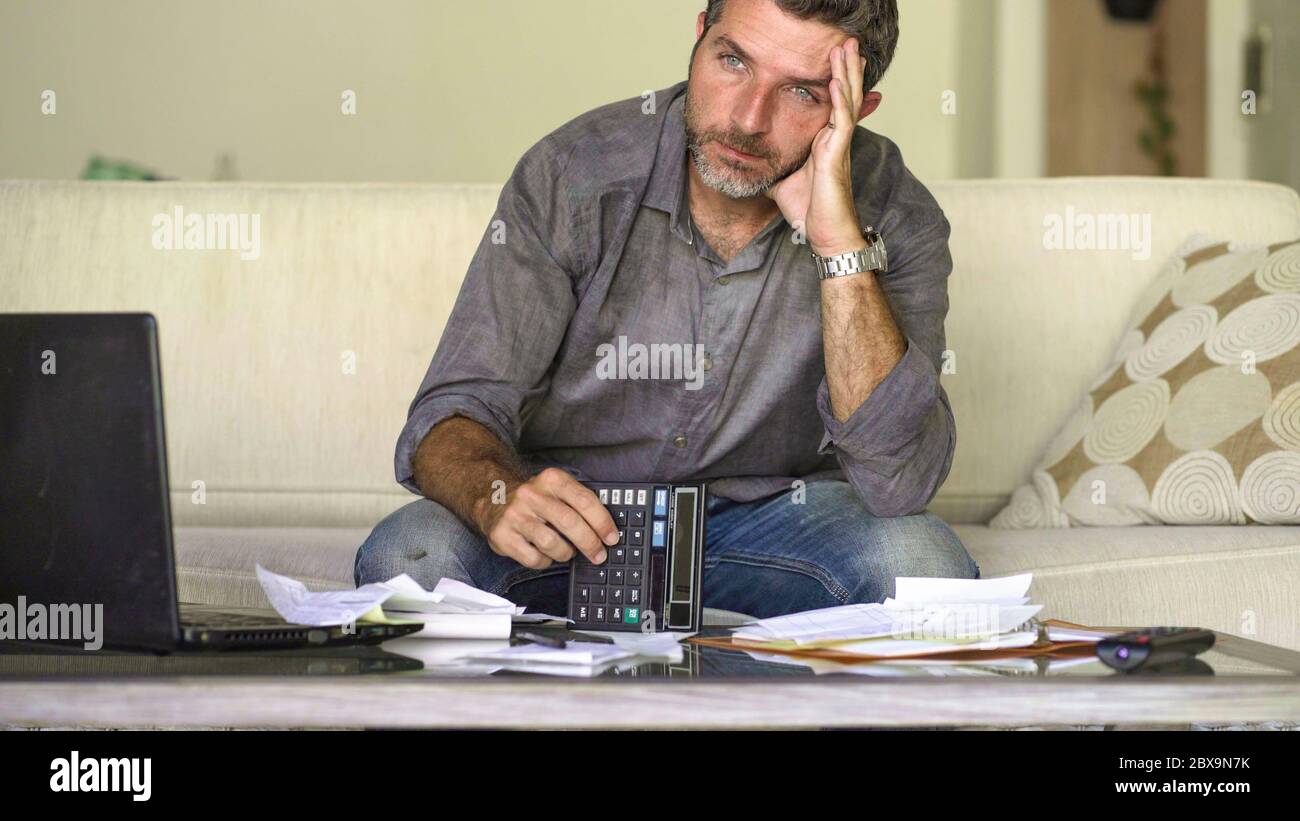 young stressed and desperate man at home living room couch doing ...