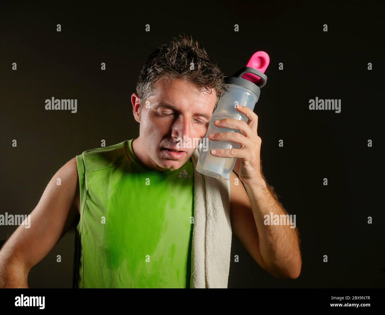 young sweaty tired and exhausted sport man with water bottle cooling ...