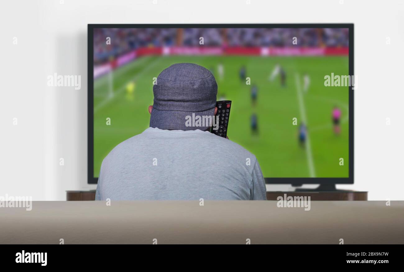 view from behind of young soccer fan man watching European football ...