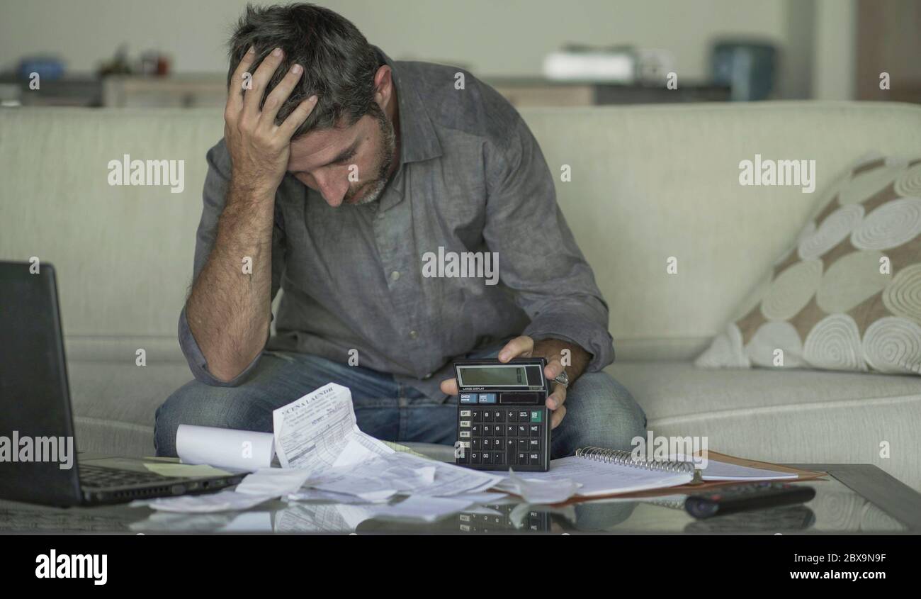 young stressed and desperate man at home living room couch doing ...
