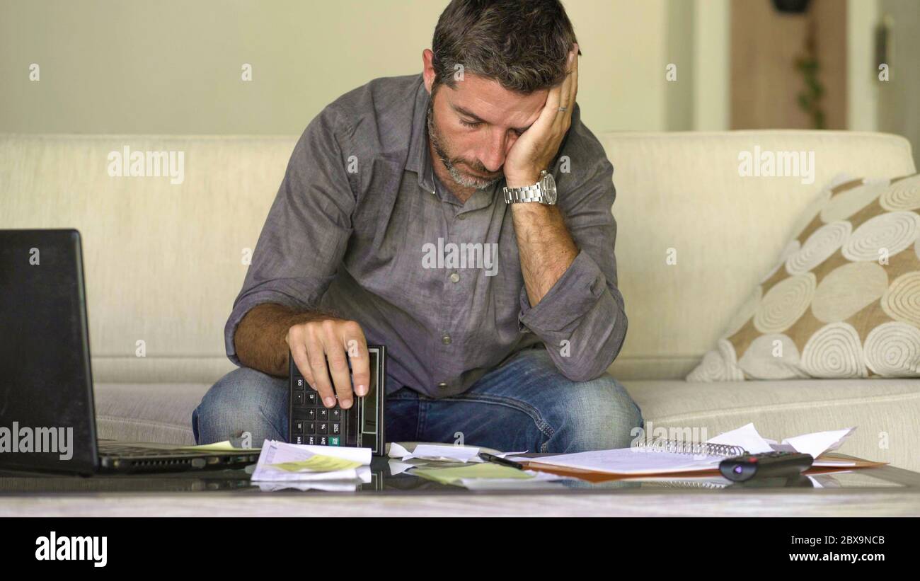 young stressed and desperate man at home living room couch doing ...