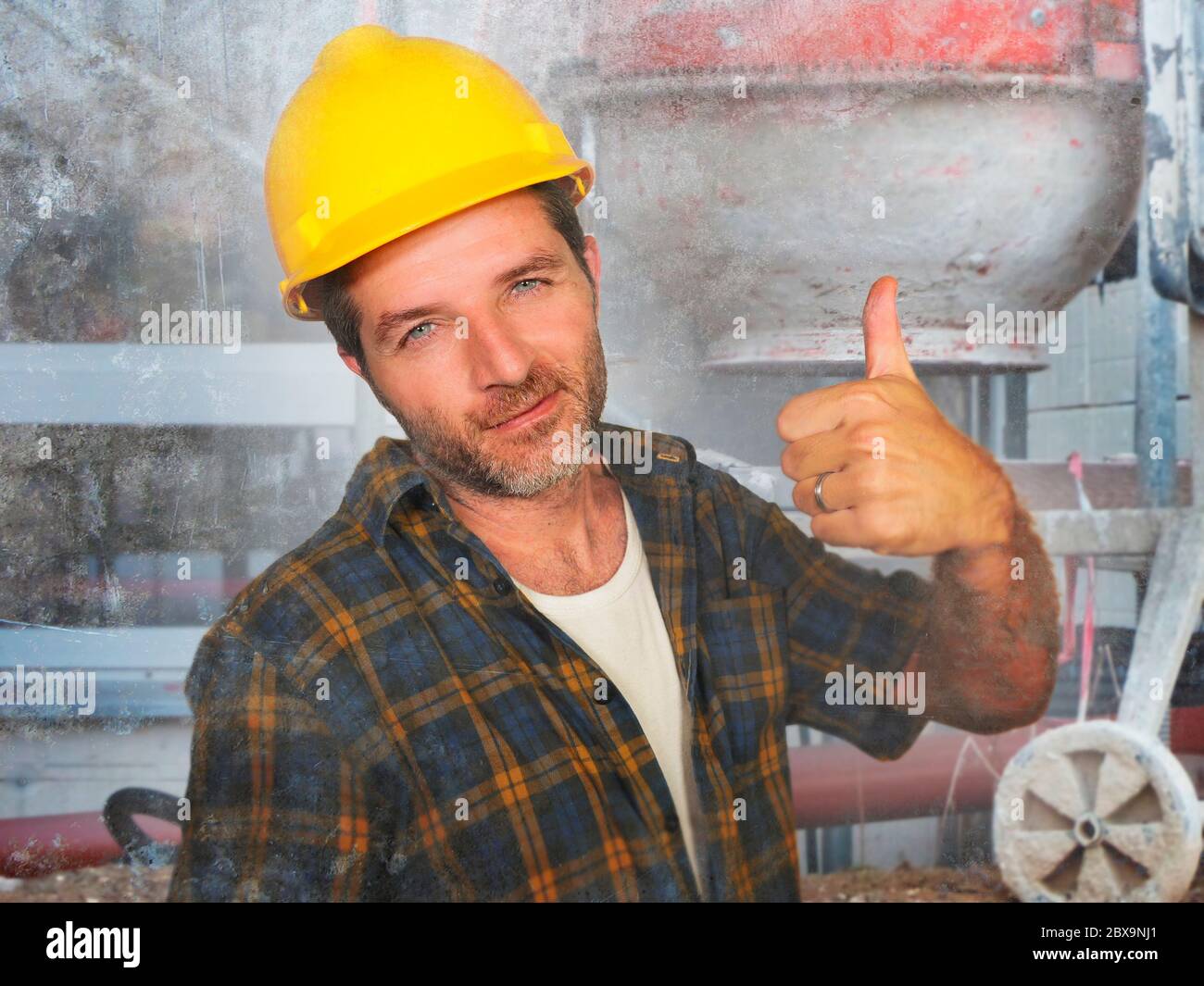 lifestyle portrait of young attractive and confident contractor or construction worker man with ...