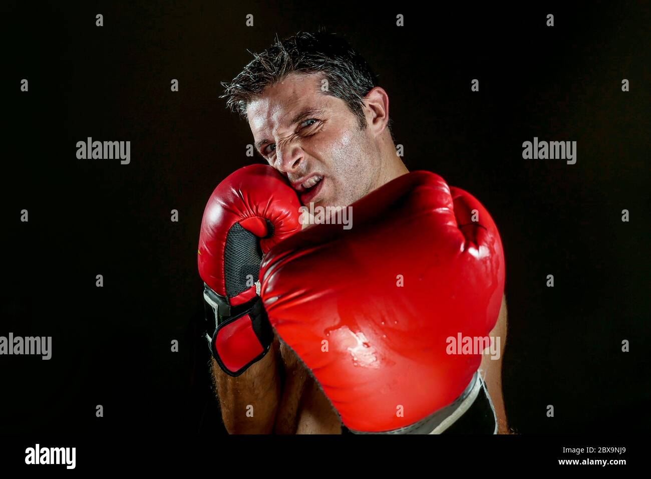 young angry and fierce sport man in boxing gloves posing in badass ...