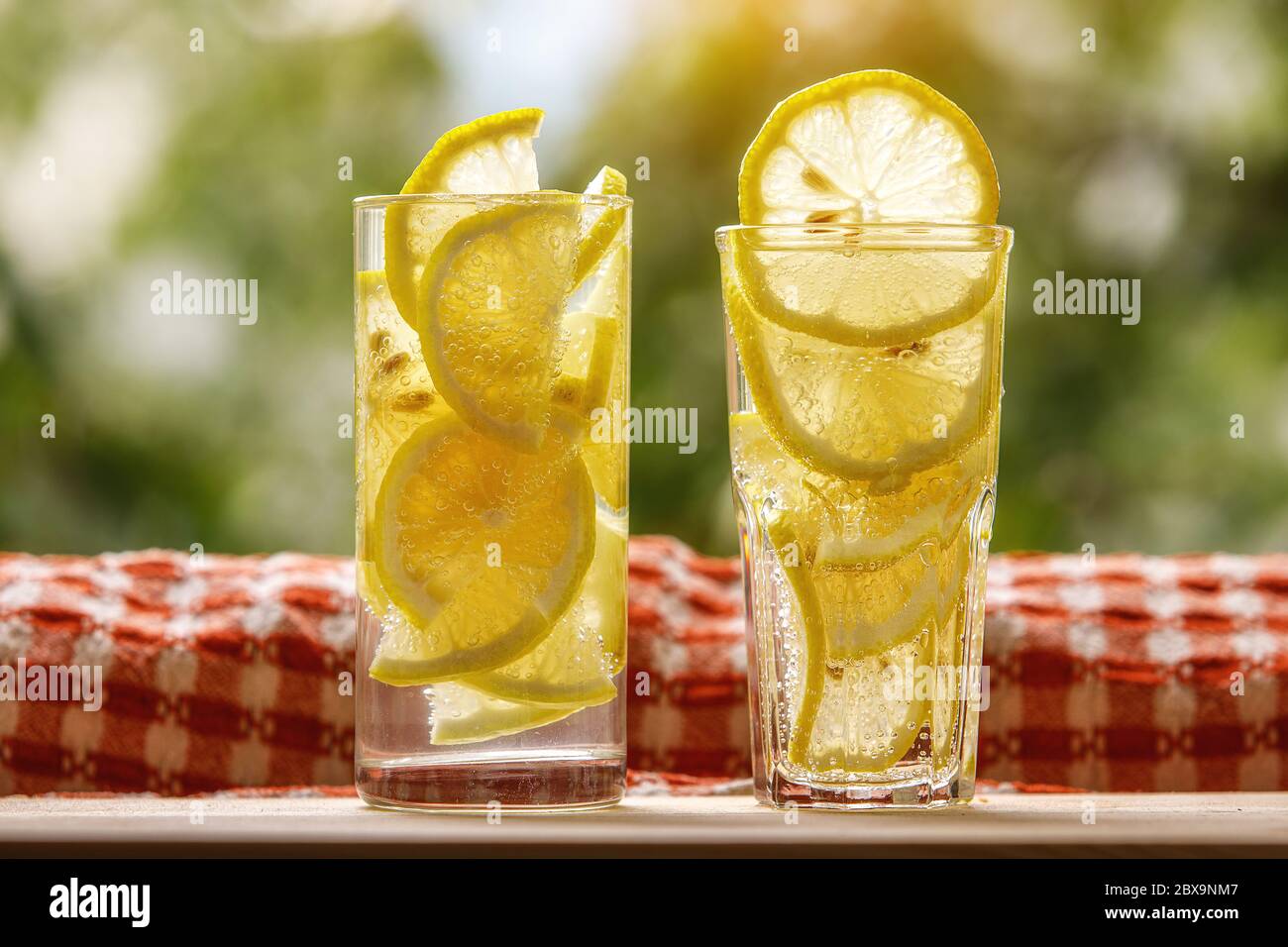 Glasses of lemonade with lemon on the sunny garden background Stock ...