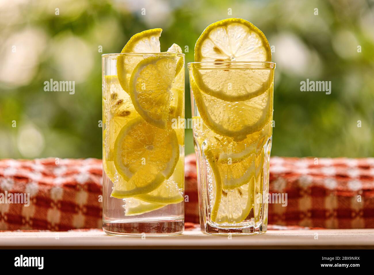 Glasses of lemon water on the sunny garden background Stock Photo - Alamy