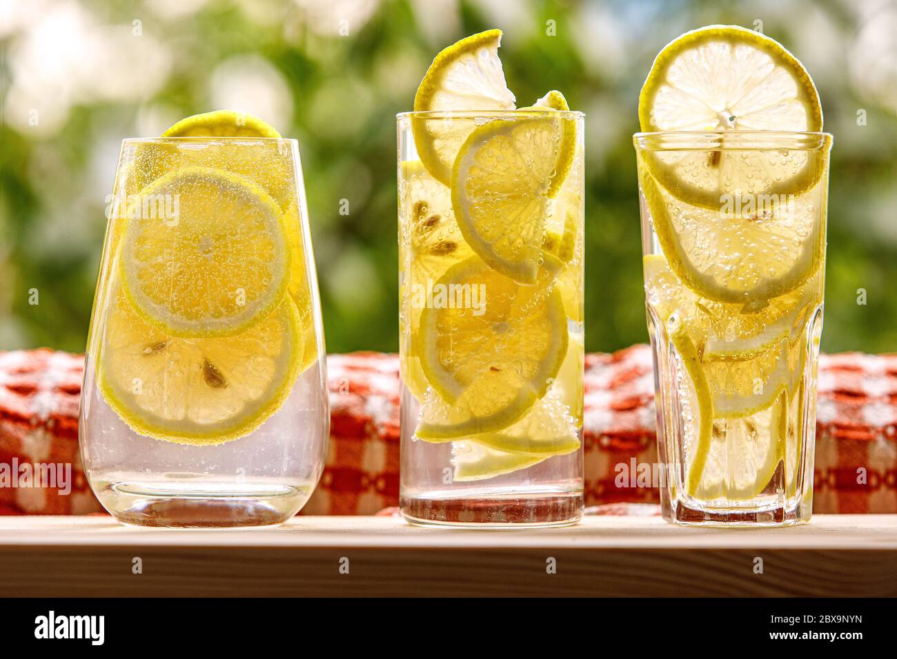 Glass of lemon water on sunny garden background Stock Photo - Alamy