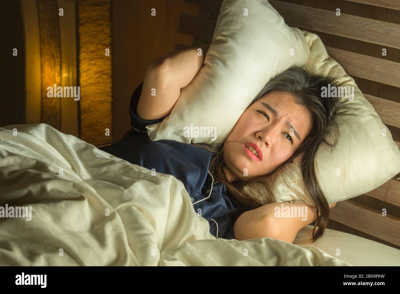 young sleepless beautiful and scared Asian Chinese woman lying on bed ...