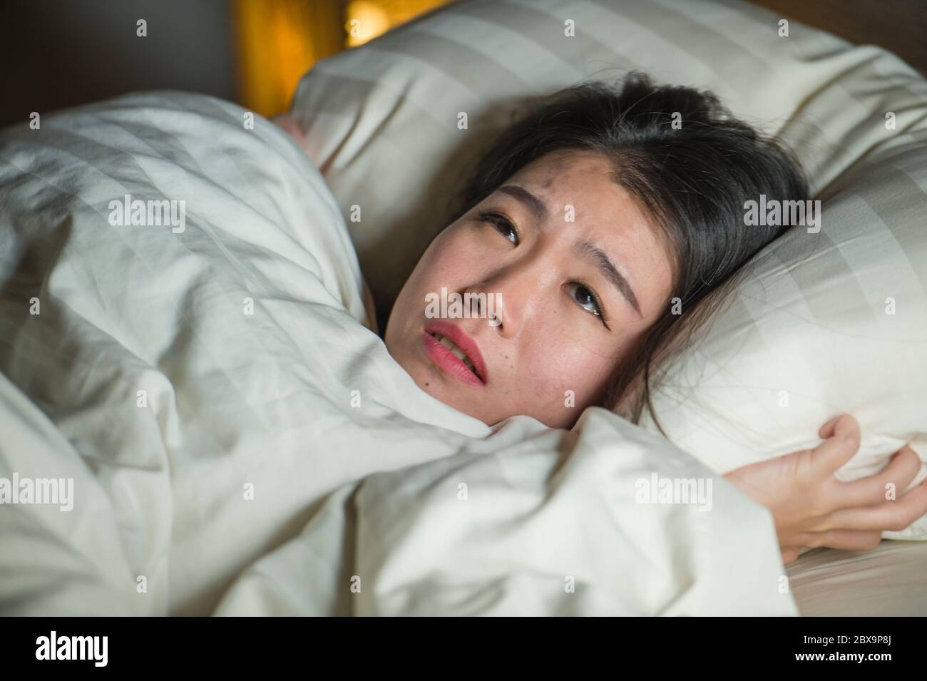 young sleepless beautiful and scared Asian Chinese woman lying on bed ...