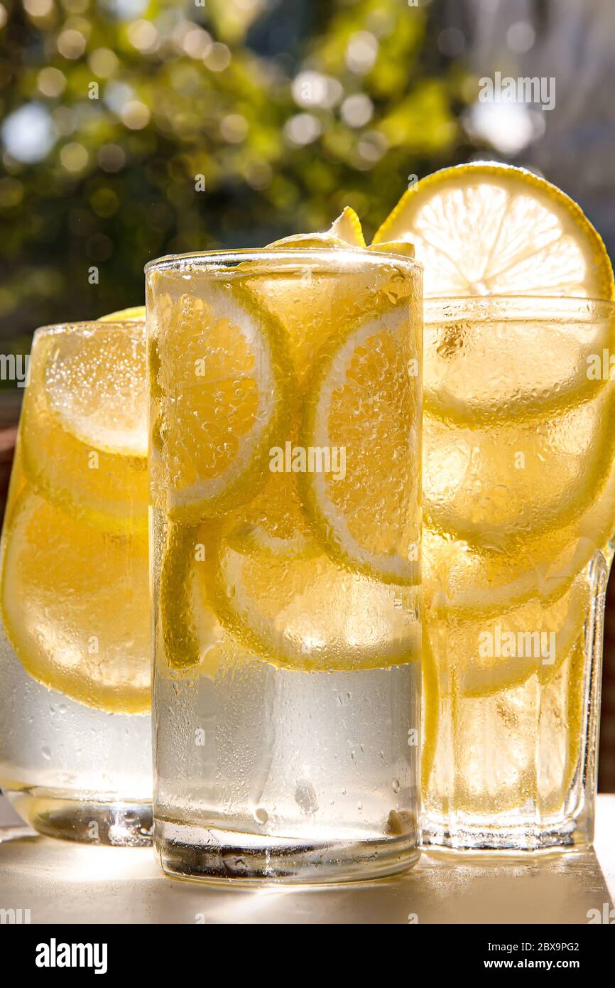 Glass of lemon water on sunny garden background Stock Photo - Alamy
