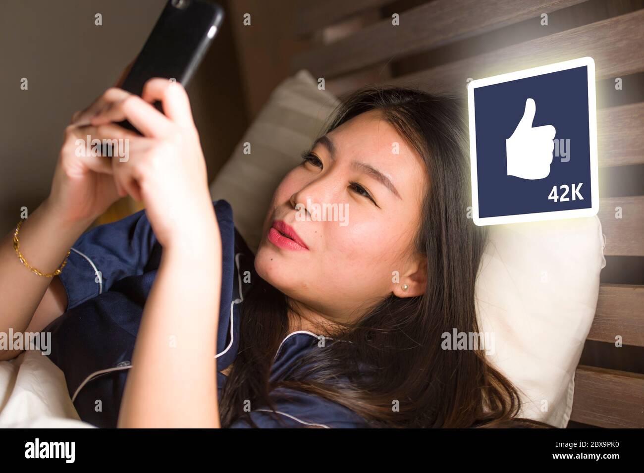 young beautiful and happy Asian Korean woman in pajamas using mobile ...