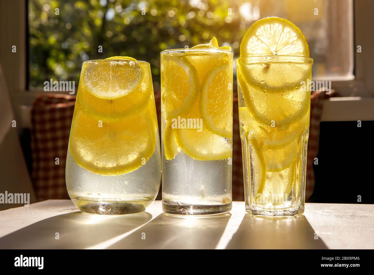 Glasses of lemonade with lemon on the sunny room background Stock Photo ...