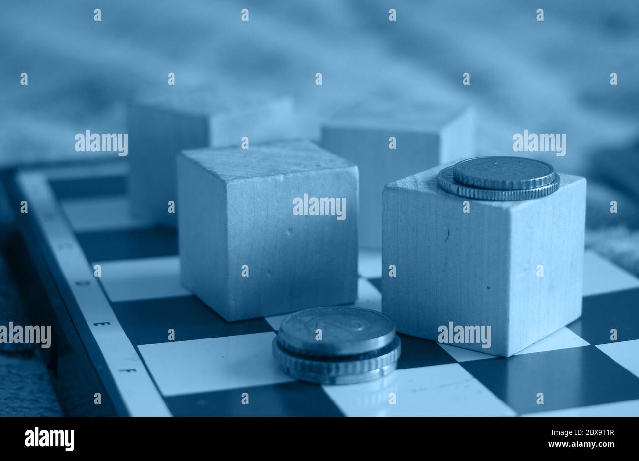 Coins on chess board and wooden cubes, concept business background ...
