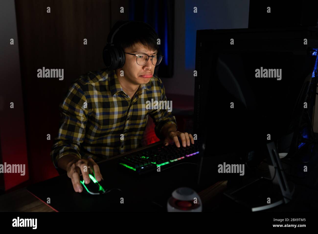 Asian man gamer in headphones stressed with hand feel depressed or ...