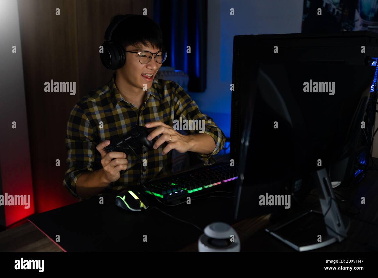 Handsome excited asian gamer guy in headphones enjoy and rejoicing ...