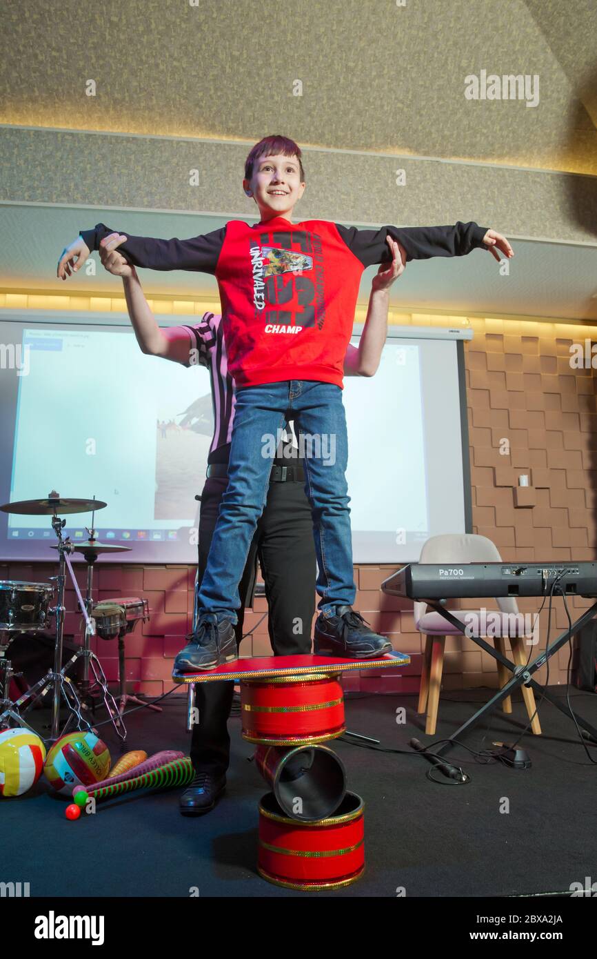 Kids standing on top of cylinders and juggling glass bottles, one ...