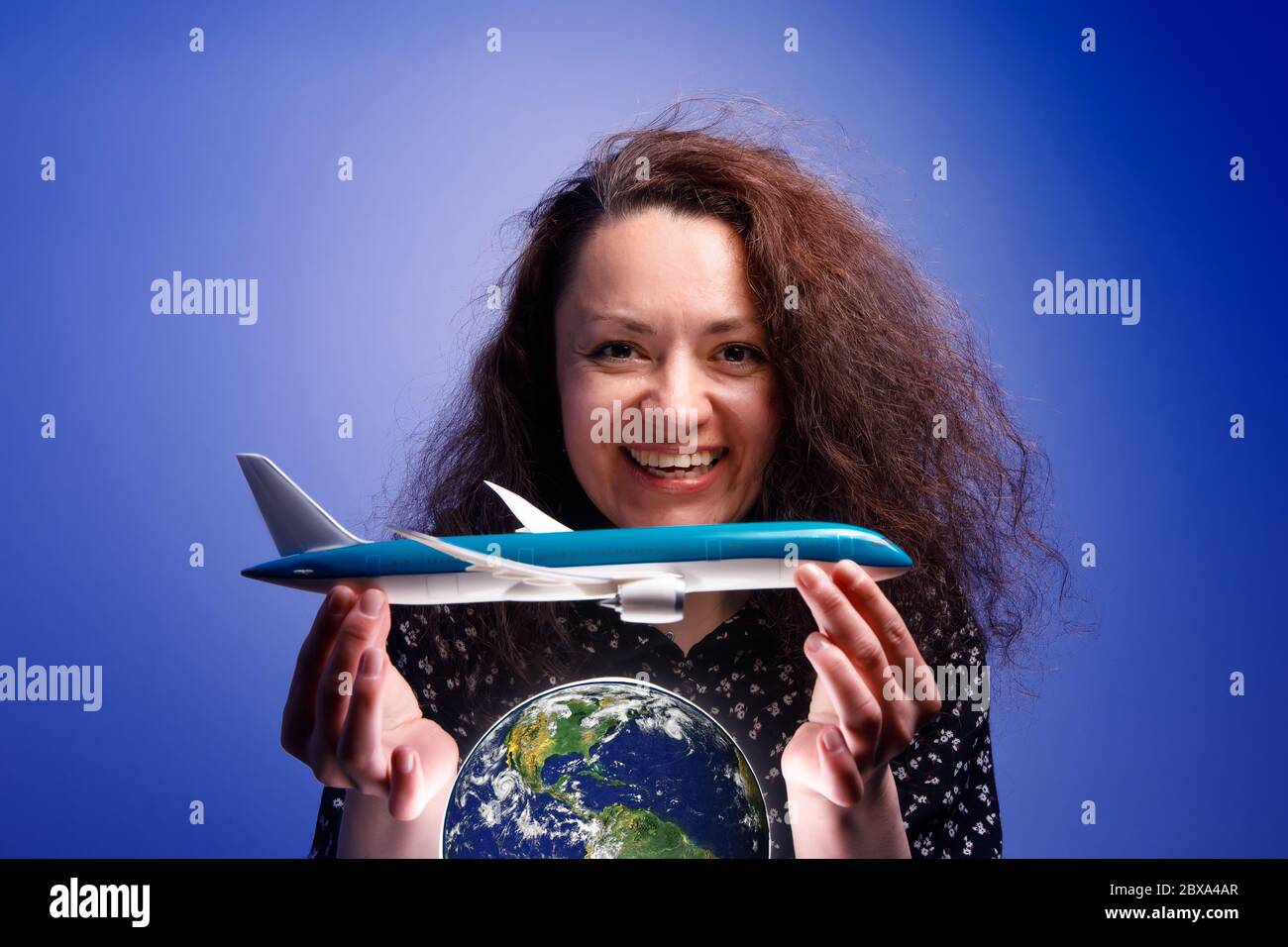 Girl with an airplane model in her arms over an earth globe. Concept of ...