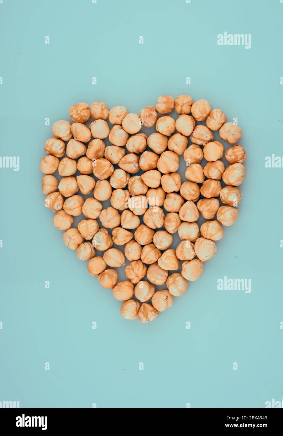 Organic hazelnuts, heart shaped on blue background Stock Photo - Alamy