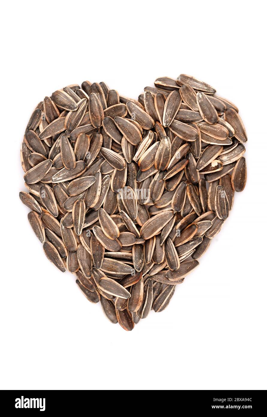 Organic Sunflower seed arrangement in heart shape on white background ...