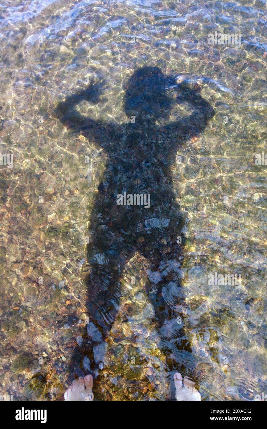 woman silhouette shadow on water, on river shore with pebbles Stock ...