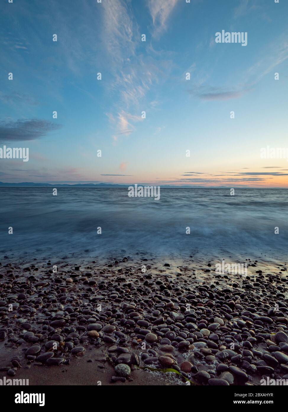 Pebbles along beach with waves and amazing sky Stock Photo - Alamy