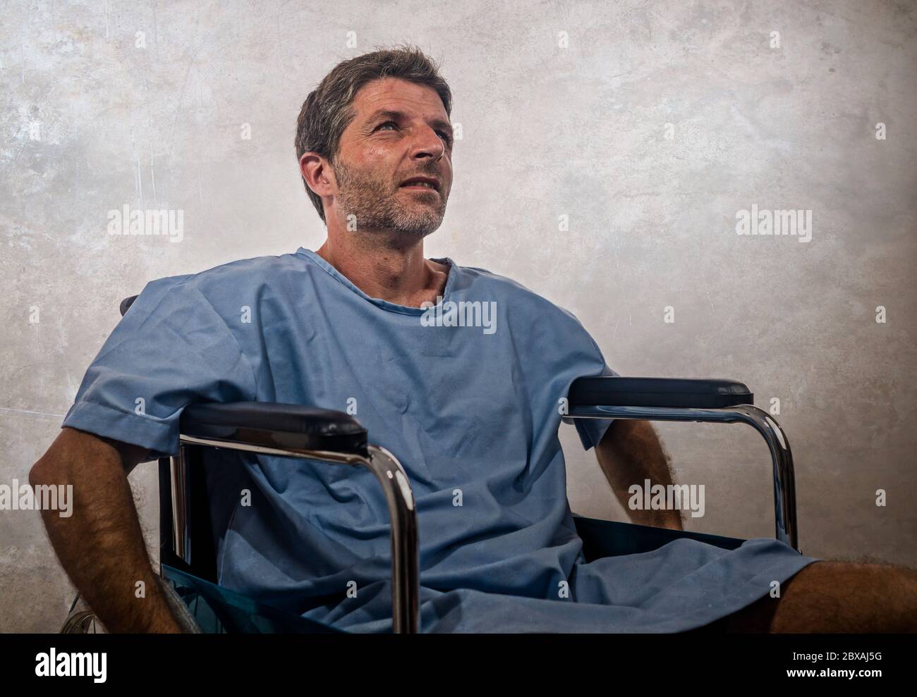 young depressed and frustrated injured man in hospital patient gown ...